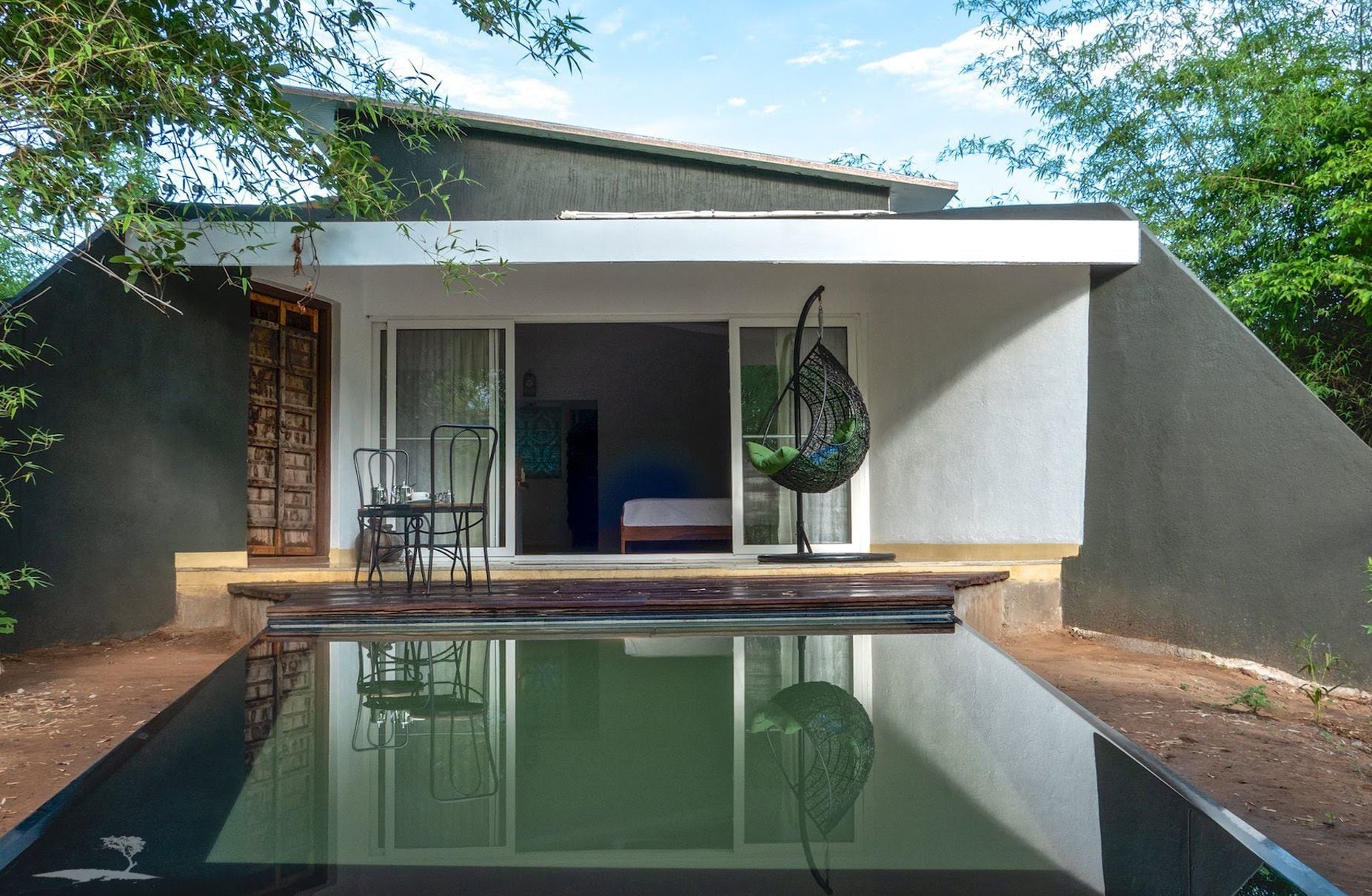 Uma casa moderna com piscina, área de jantar com cadeiras e uma cadeira suspensa.