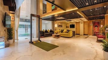 Um saguão de hotel com balcão de recepção, área de estar e uma grande janela.