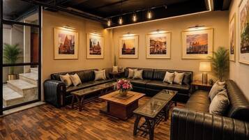 Um saguão de hotel moderno com piso de madeira, sofás de couro, uma mesa de centro e quadros na parede.