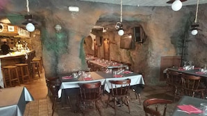 Restaurante com paredes de pedra e mesas preparadas para refeições.