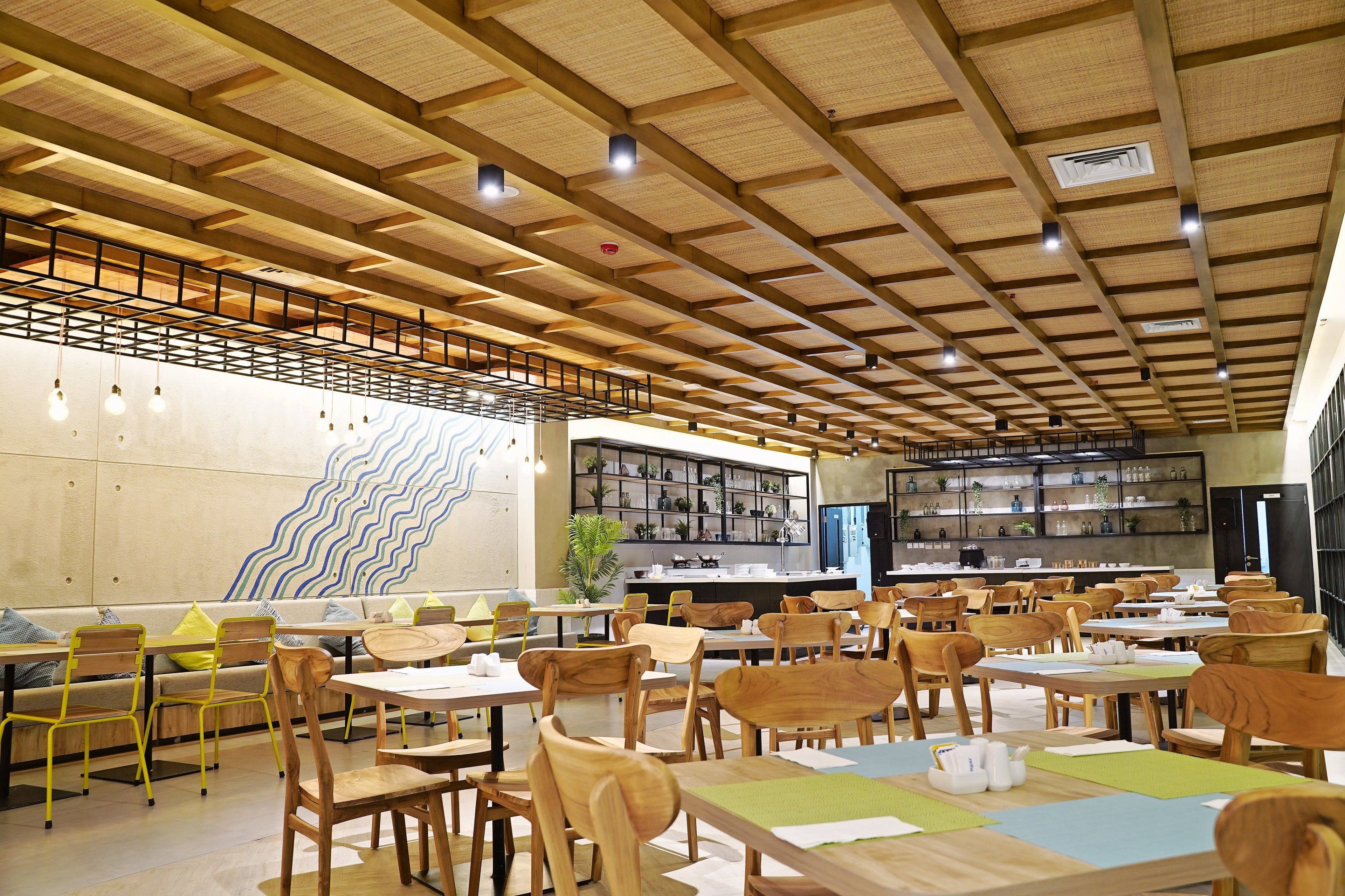 Um restaurante espaçoso com mobiliário de madeira e um design moderno no teto.