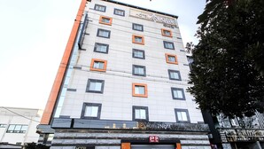 Um hotel com vários andares, com uma placa que diz "HOTEL 2Night" e uma placa de estacionamento indicando dois níveis.