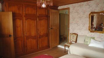 Quarto com armários de madeira, uma cama, uma cadeira e um espelho.