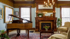 Uma sala imponente com um piano de cauda, lareira e mobiliário elegante.