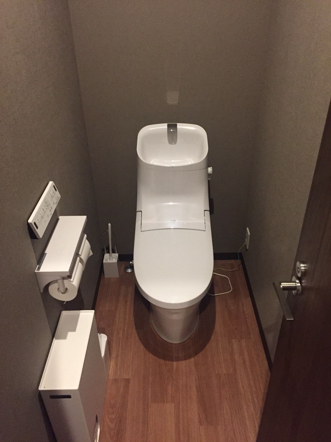 Um banheiro pequeno e moderno, com vaso sanitário, secador de mãos e dispensador de papel toalha.