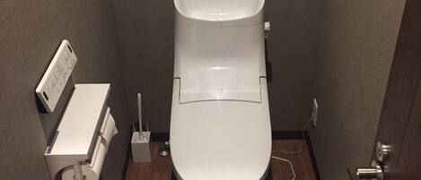 Um banheiro pequeno e moderno, com vaso sanitário, secador de mãos e dispensador de papel toalha.