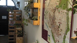 Quarto com um mapa grande na parede, estantes de madeira com plantas e uma mesa branca com cartões informativos.