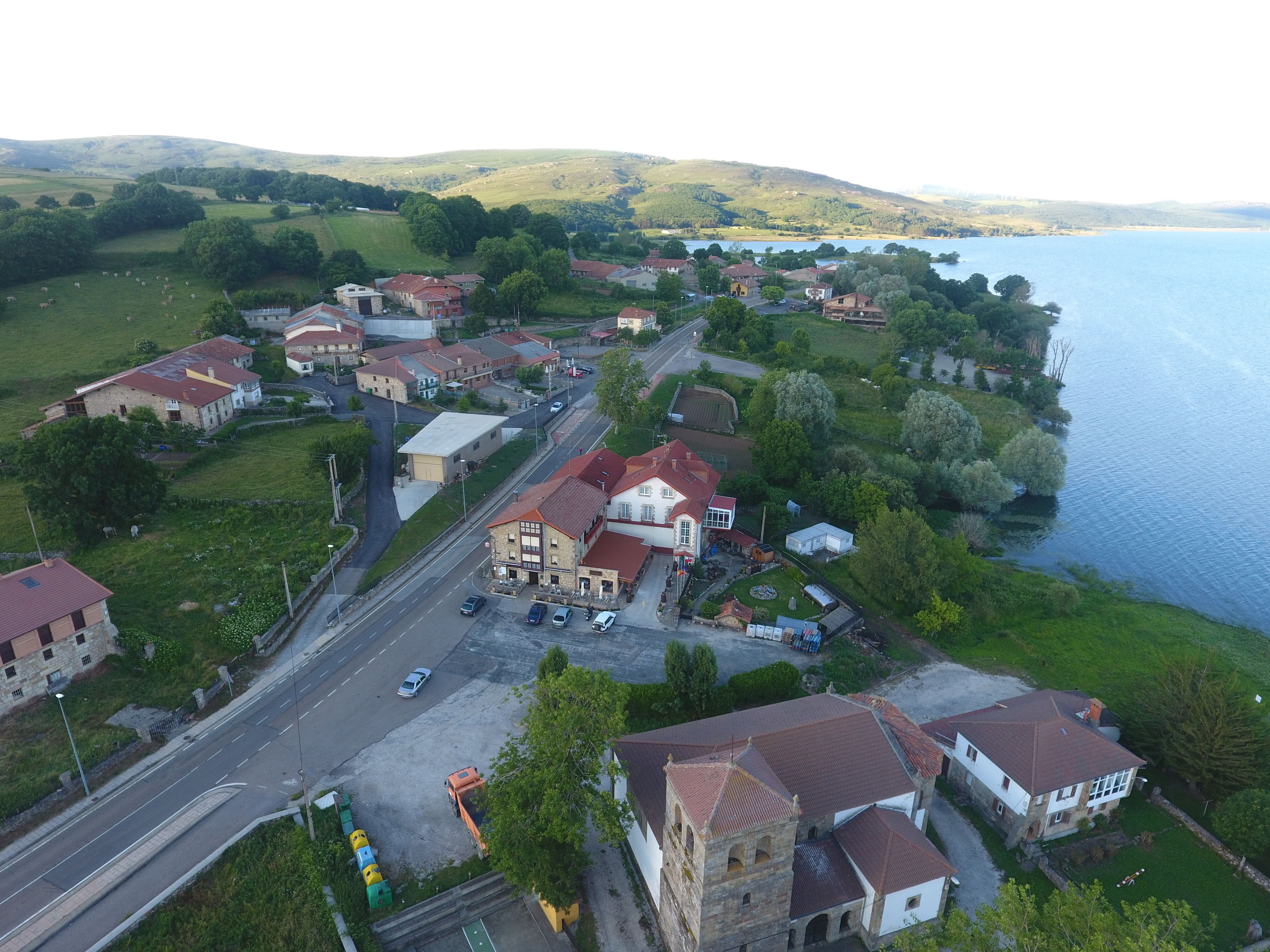 Vista aérea de uma vila costeira com casas, uma estrada e um corpo d'água.