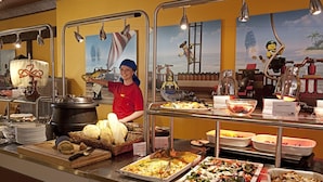 Uma área de buffet com diversas opções de comida, um funcionário e decoração com tema náutico.