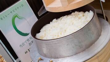 Uma panela de metal grande cheia de arroz branco sobre um suporte de madeira.