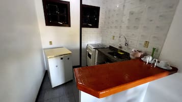 Cozinha compacta com geladeira, fogão e pia.