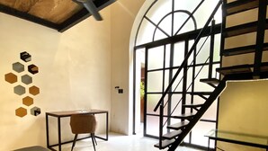 Um interior moderno com um sofá, uma mesa, uma escada e um tapete com padrão geométrico.