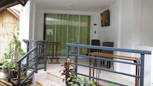 Uma escadaria leva a um quarto com porta de vidro deslizante, uma mesa e cadeiras.