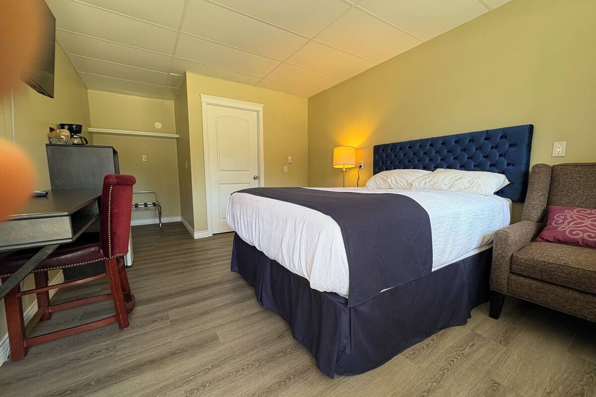 Quarto de hotel com cama, escrivaninha, cadeira e sofá.