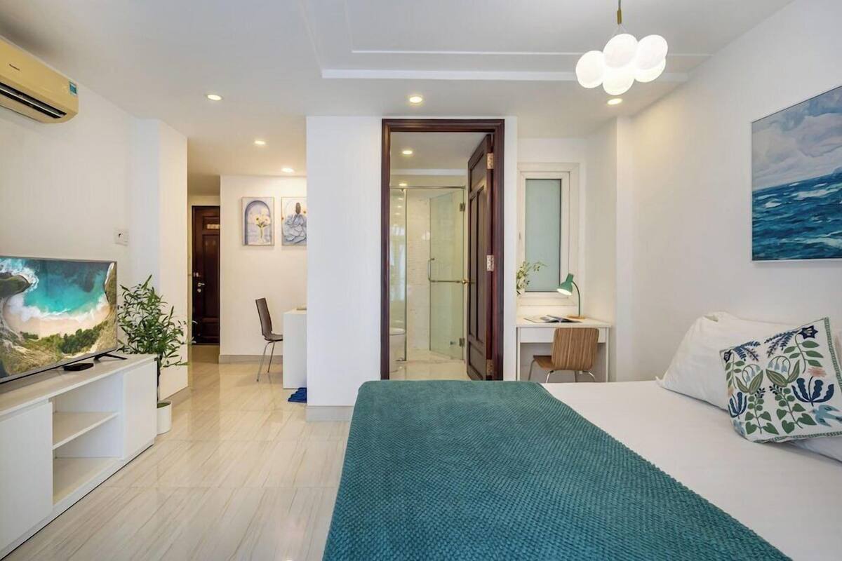 Quarto de hotel moderno com cama, escrivaninha e televisão.
