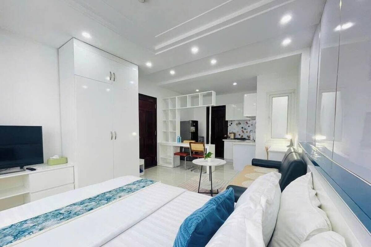 Quarto de hotel moderno com cama grande, televisão, área de refeições e cozinha.