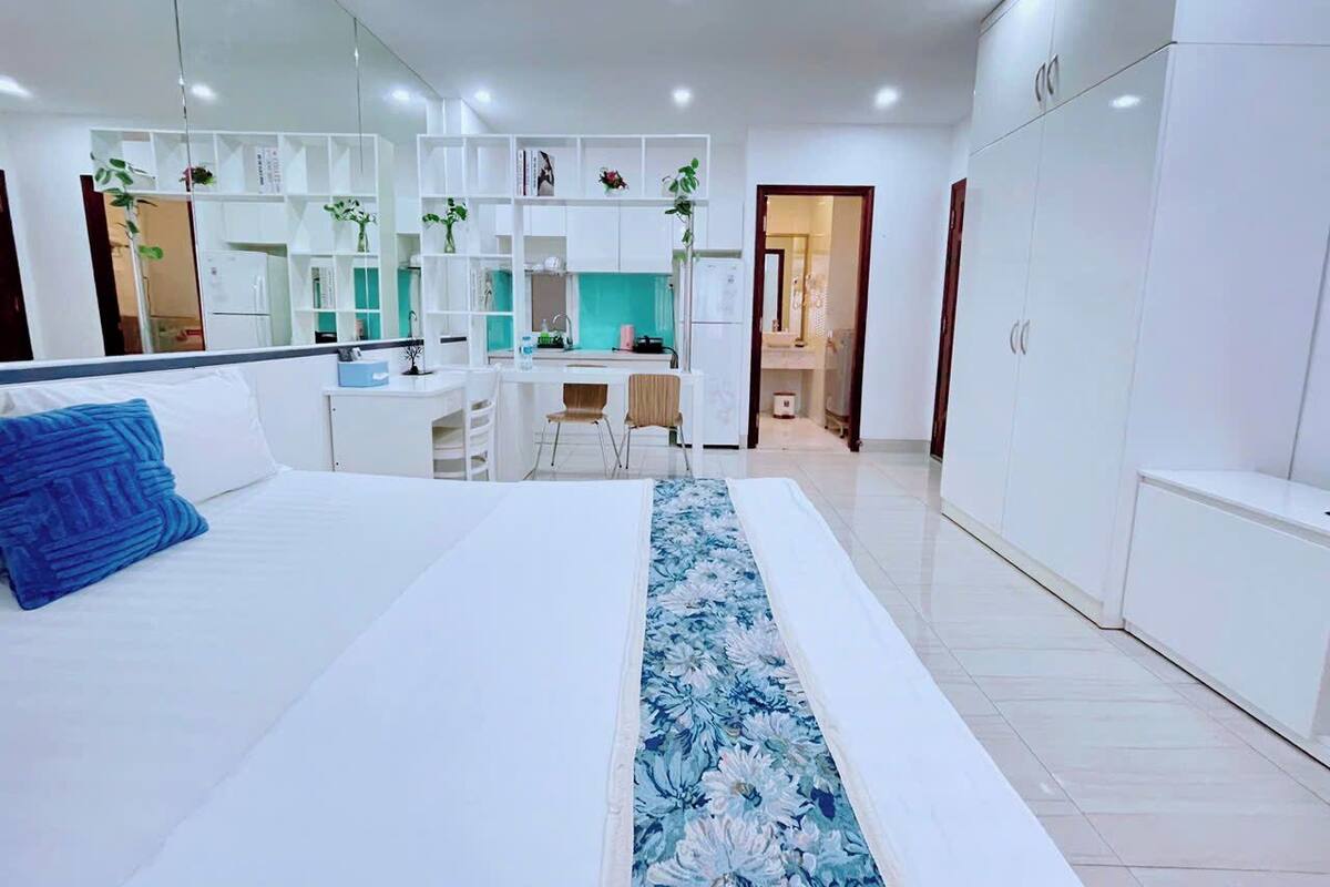 Quarto de hotel moderno com uma cama grande, uma escrivaninha e uma área de cozinha compacta.