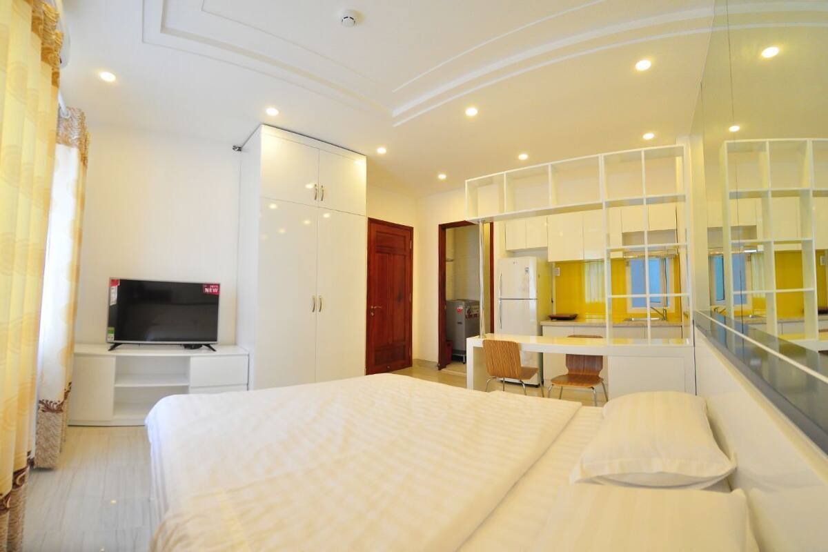 Quarto de hotel com cama, televisão, escrivaninha e cadeira.