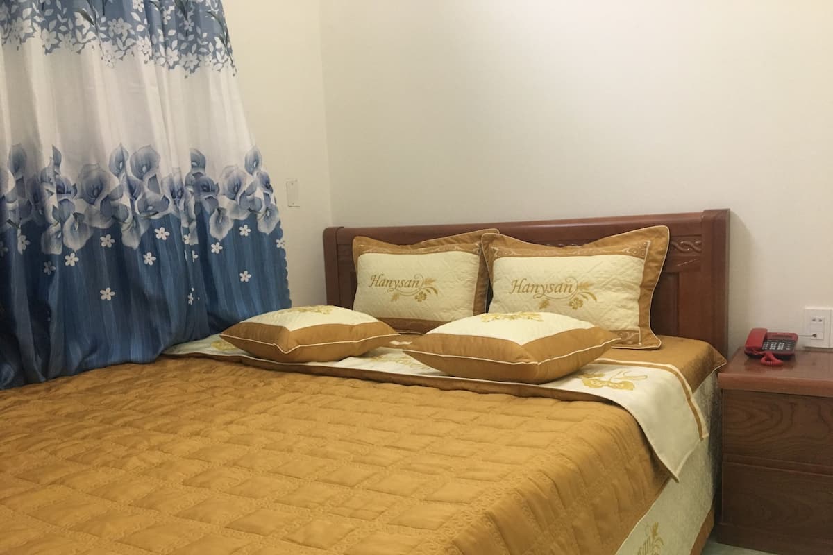 Uma cama bem arrumada com edredom acolchoado e duas almofadas com a inscrição 'Hanysan'.