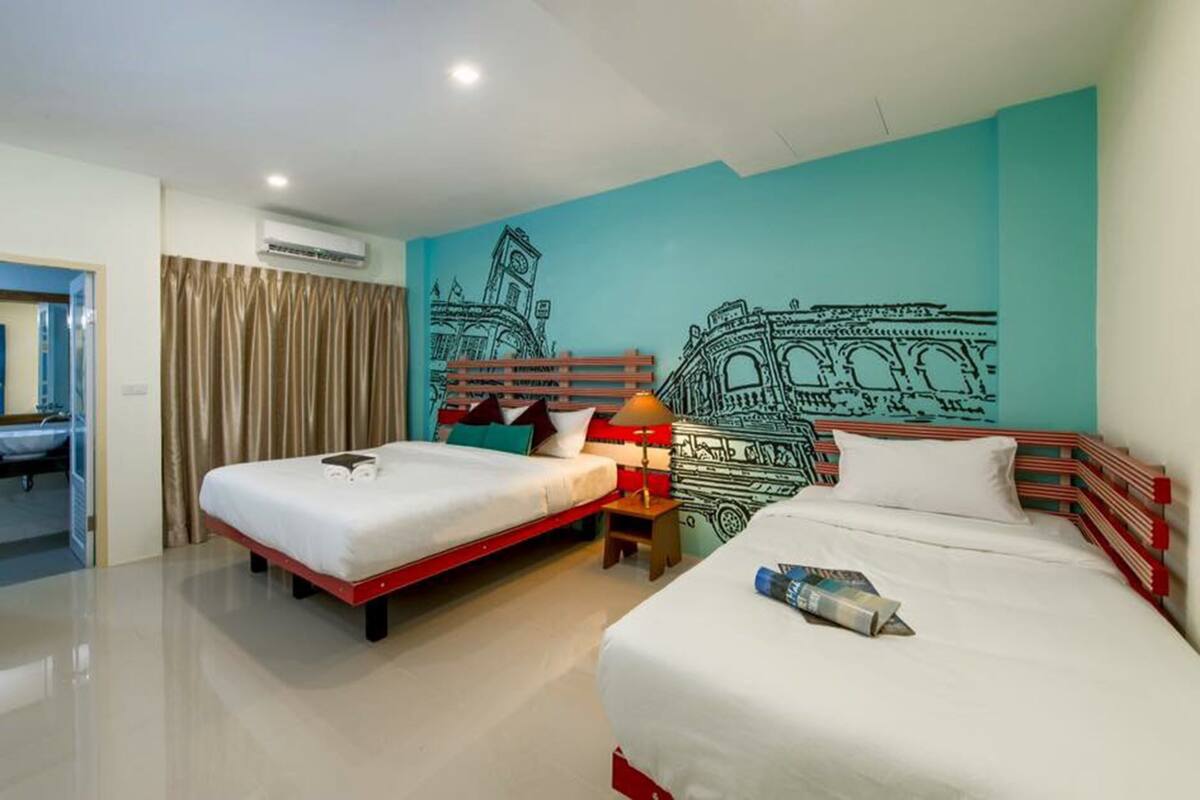 Quarto de hotel com duas camas, um mural de um edifício histórico e banheiro com banheira.