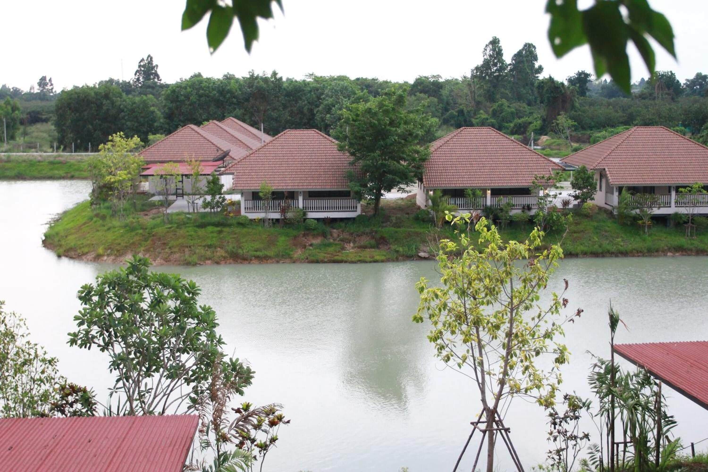 Fileira de edifícios no estilo de bangalôs, com telhados vermelhos e paredes brancas, localizada à beira de um lago tranquilo.