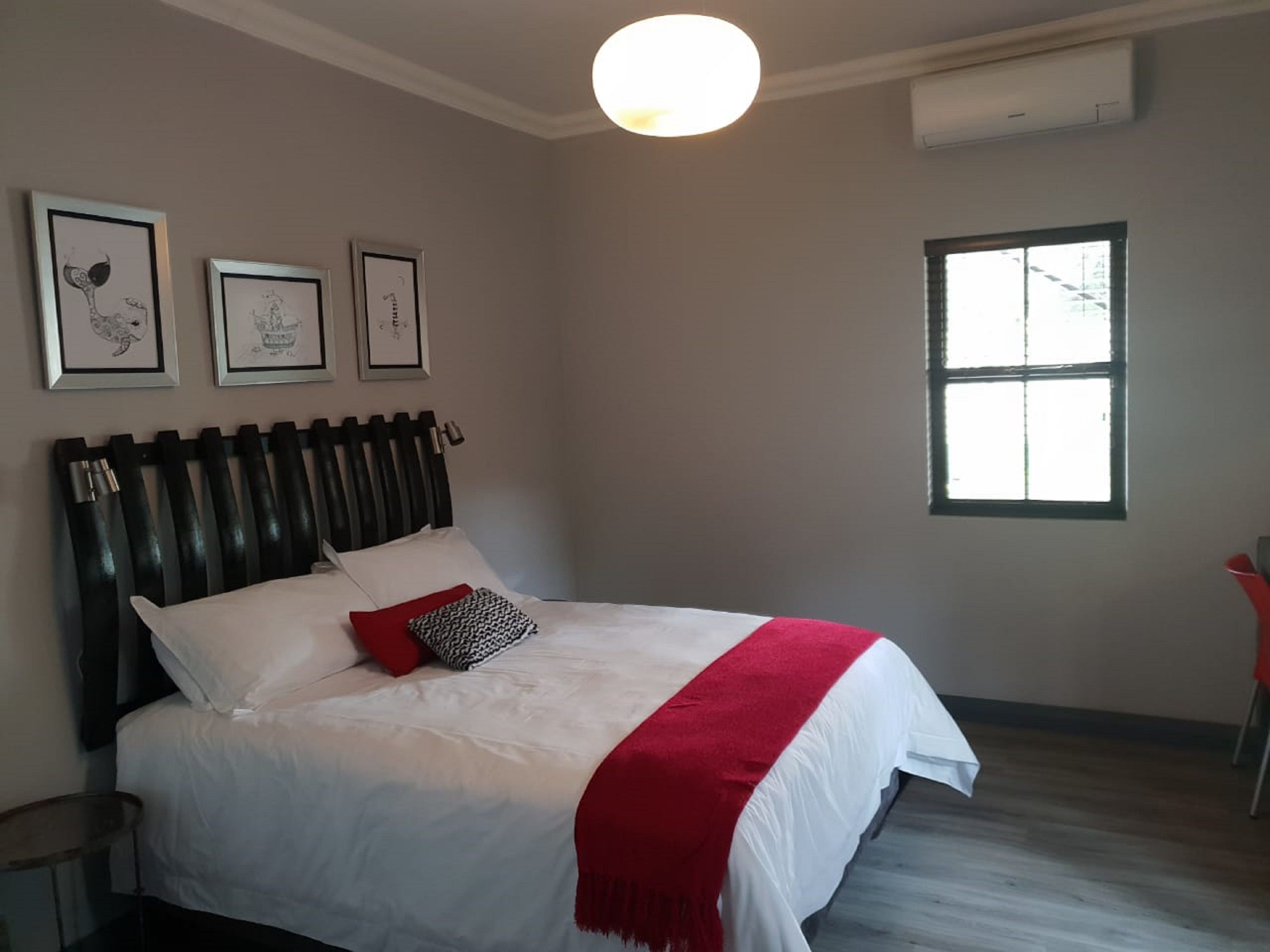 Quarto com uma cama, uma janela e três quadros na parede.