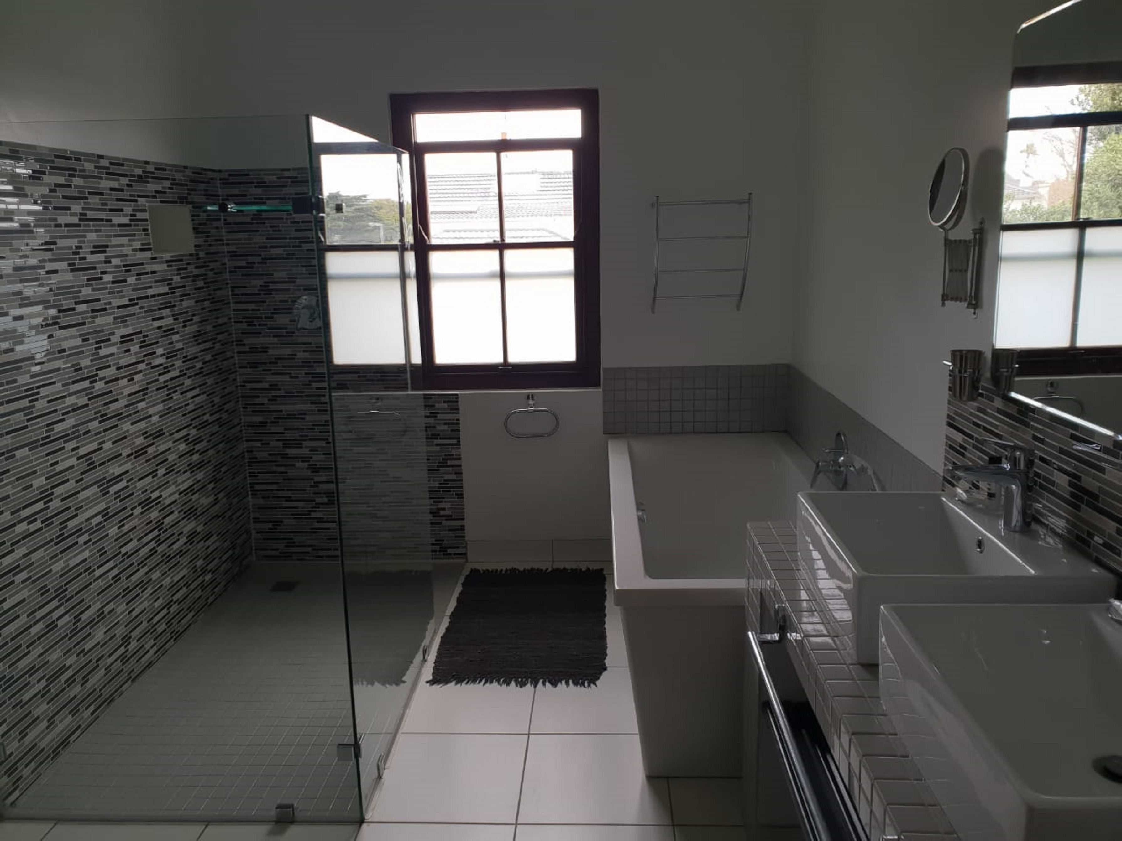 Casa de banho moderna com cabine de duche em vidro, banheira e toucador com espelho.
