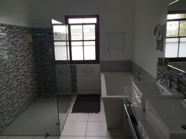 Casa de banho moderna com cabine de duche em vidro, banheira e toucador com espelho.