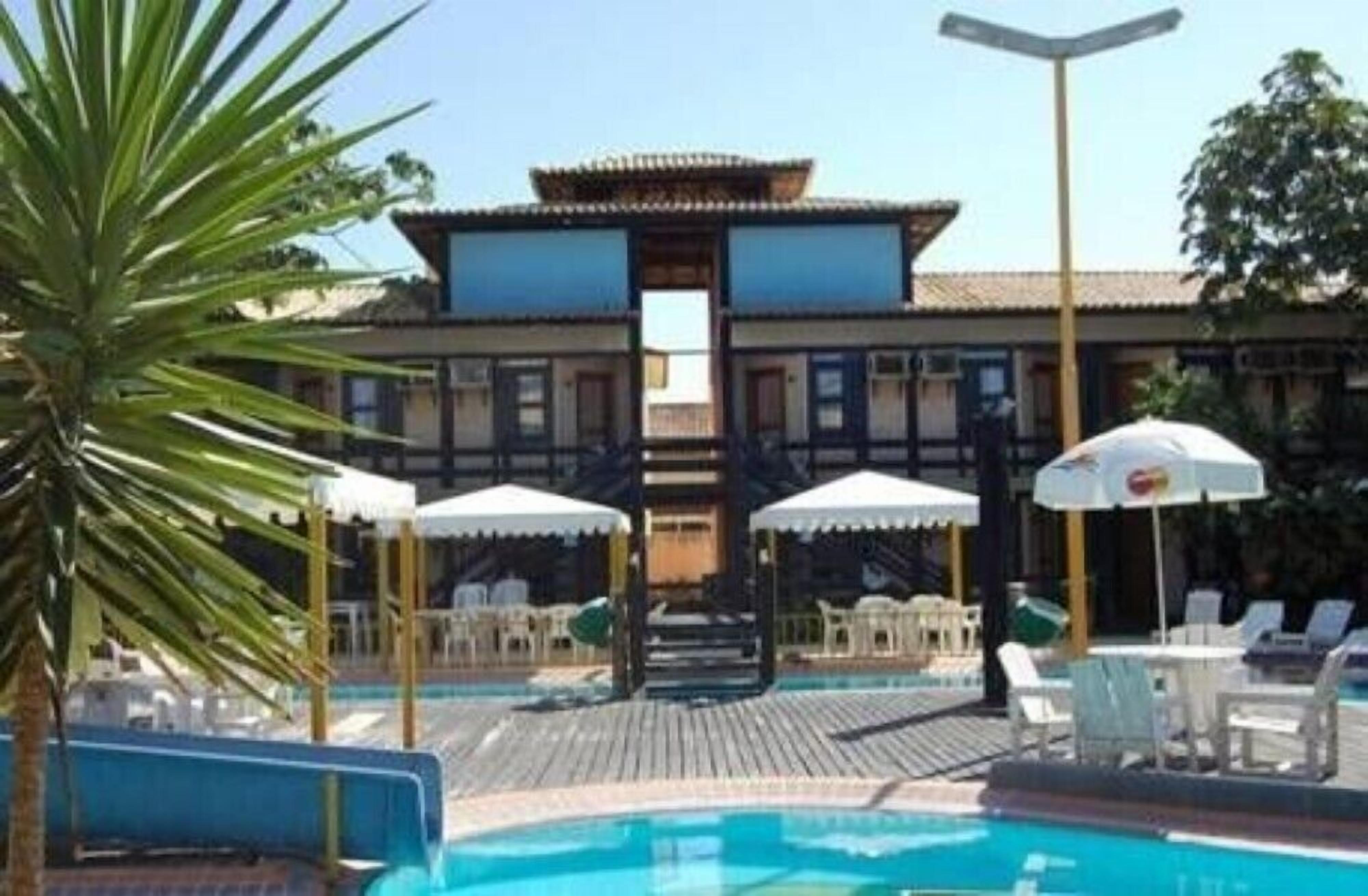 Um hotel com área de piscina, incluindo cadeiras de espreguiçadeira e guarda-sóis.