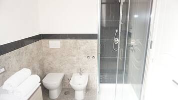 Casa de banho com sanita, bidé e cabine de duche.