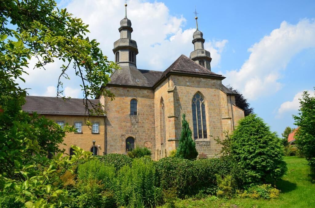 Uma igreja histórica com duas torres imponentes e um jardim bem cuidado.