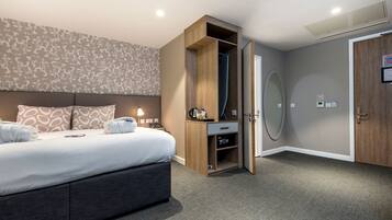Quarto de hotel moderno com uma cama grande, um guarda-roupa, um espelho e uma porta.