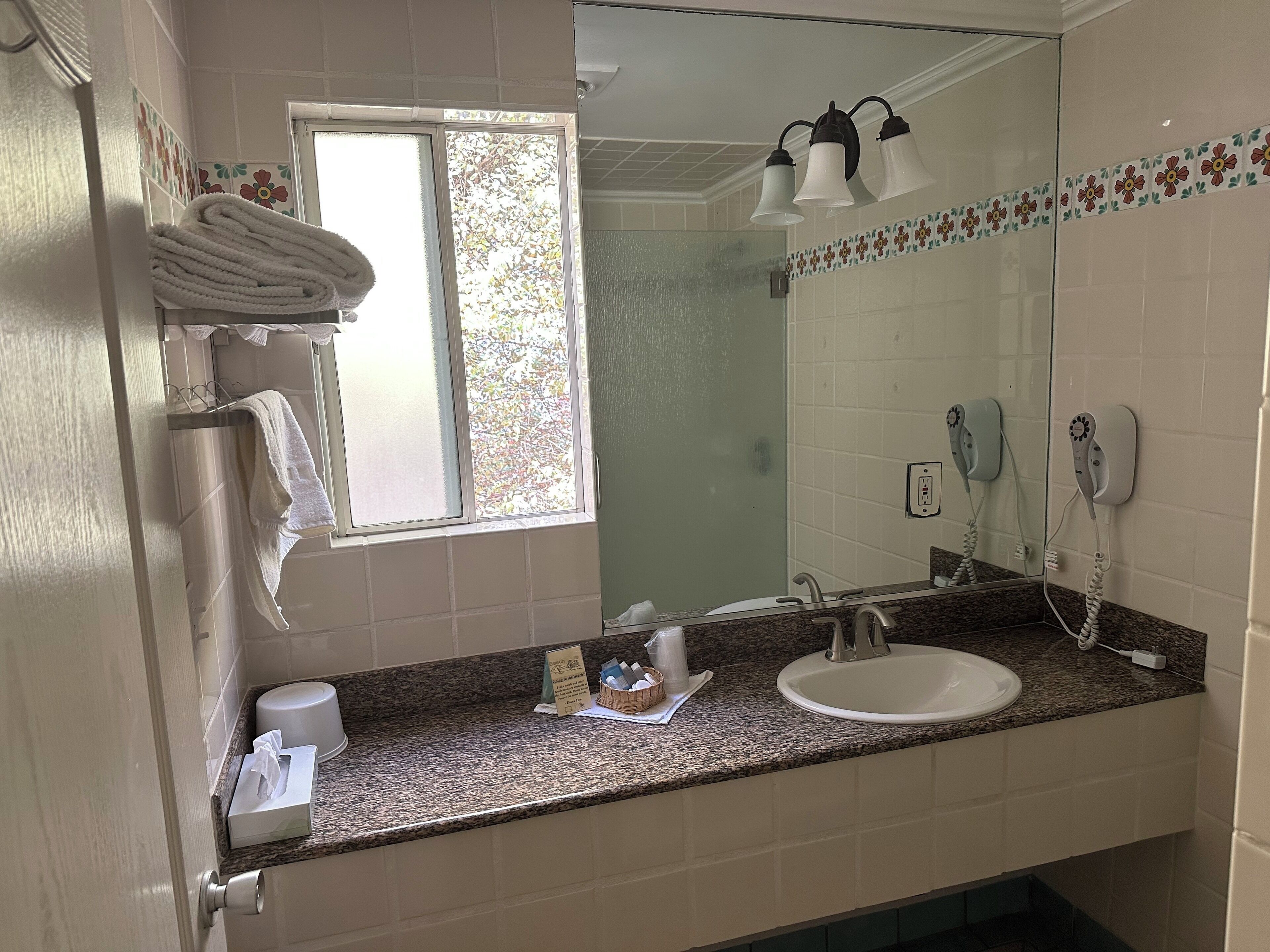 Casa de banho com lavatório, porta-toalhas e espelho com secador de cabelo.