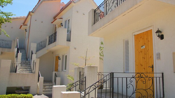 Um edifício residencial de vários andares, com varandas, uma porta de madeira e uma escadaria.
