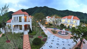 Um hotel com um pátio central, uma fonte e montanhas ao fundo.