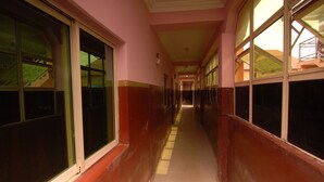 Um corredor comprido e estreito, com amplas janelas em ambos os lados, que leva a uma escadaria no final.