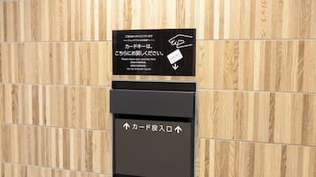 Leitor de cartão fixado na parede, com instruções em japonês e uma seta apontando para cima.
