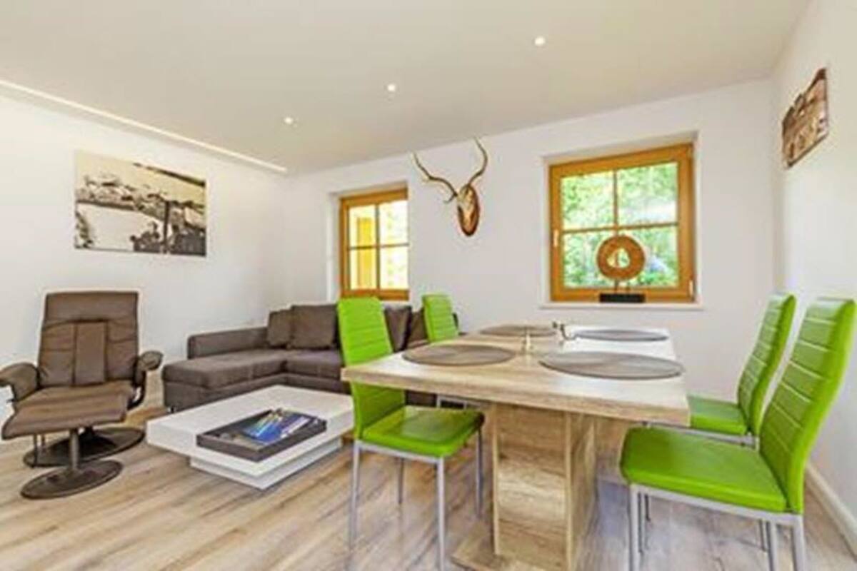 Uma sala de estar moderna com um sofá, cadeiras, uma mesa de jantar e um cabeça de veado fixada na parede.
