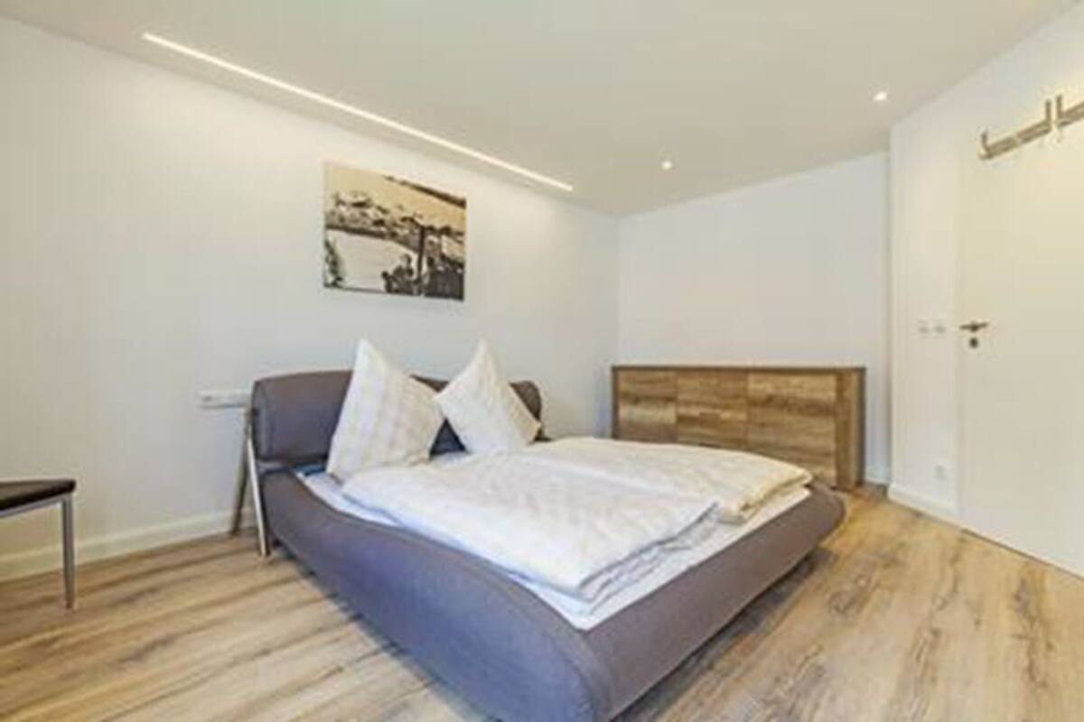 Quarto moderno com cama, mesa de cabeceira e prateleira na parede.