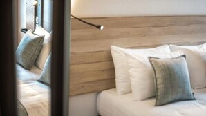 Cama bem arrumada com cabeceira de madeira e dois travesseiros.