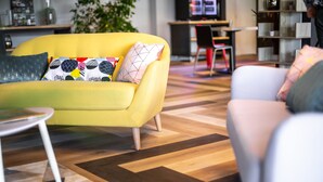Uma sala de estar moderna com um sofá amarelo, um sofá branco e uma mesa redonda pequena.