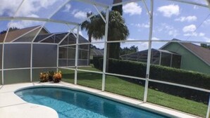 Uma piscina com vista clara do bairro ao redor, incluindo casas e uma palmeira.