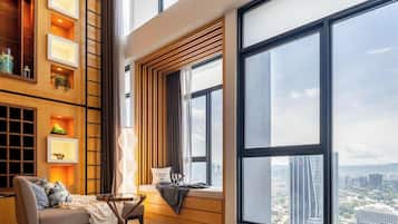 Um interior moderno com uma janela grande, um sofá, um abajur e vista para a cidade.