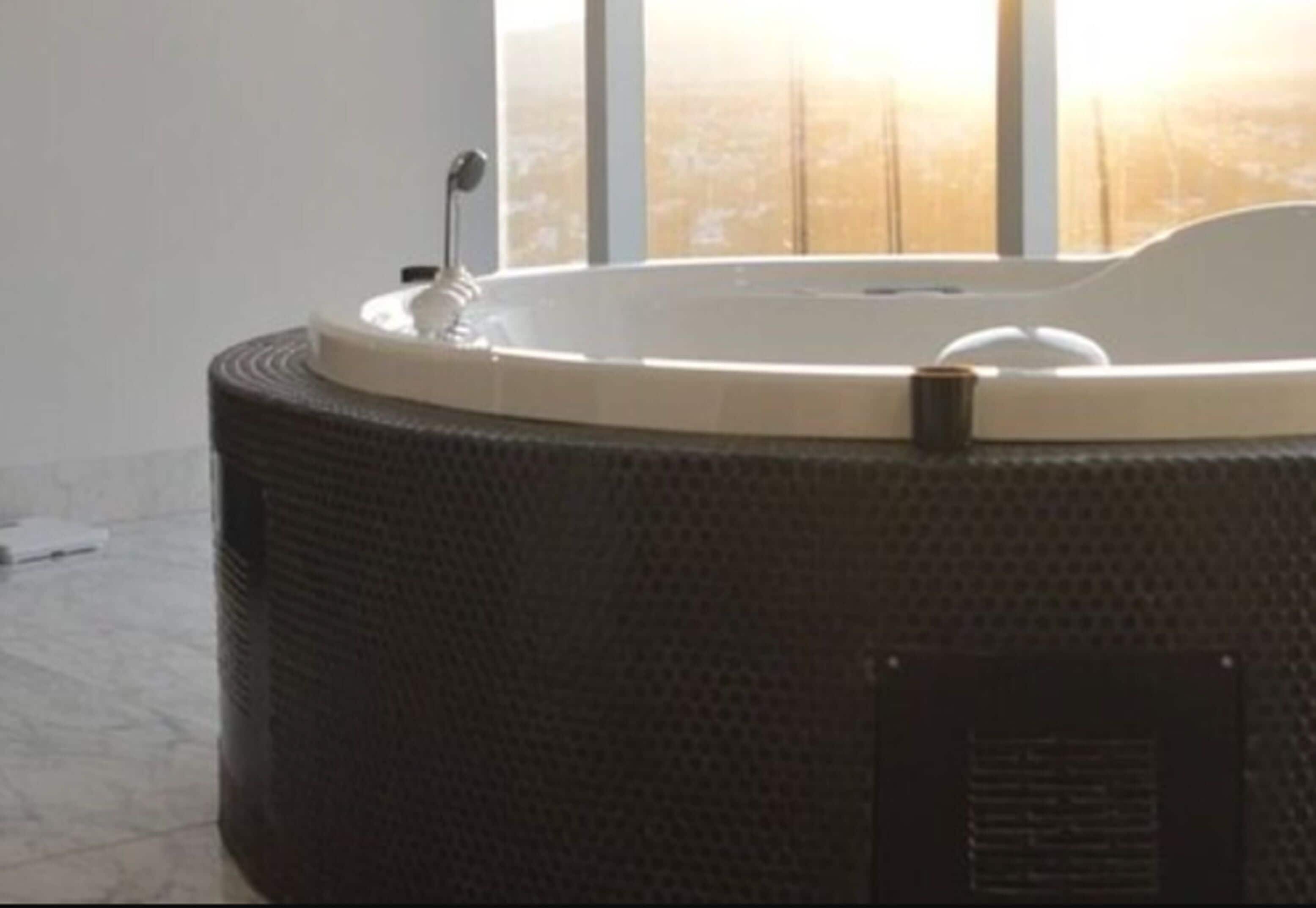 Uma banheira de hidromassagem em um quarto com uma janela grande.