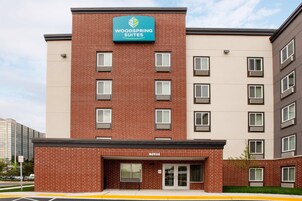 Um edifício de hotel com vários andares e uma placa chamativa para 'Woodspring Suites' na fachada.