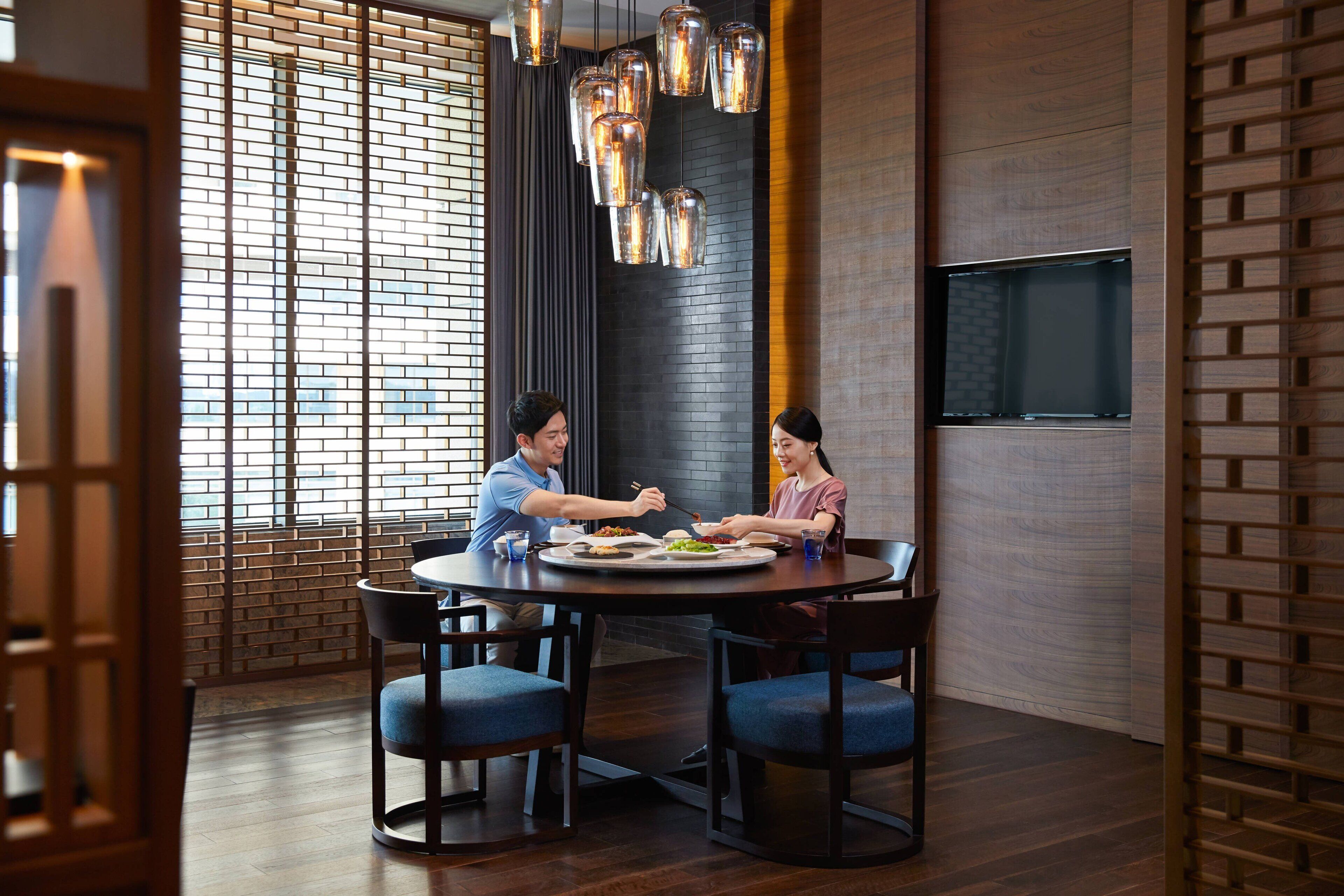 Uma sala de jantar moderna com uma mesa redonda, duas cadeiras e uma parede de tijolos.