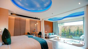 Quarto de hotel moderno com uma cama grande, uma escrivaninha, um sofá e vista para o exterior.
