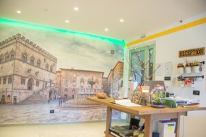 Uma área de recepção com um mural de um edifício histórico, um balcão de atendimento e uma placa com a inscrição 'RECEPTION'.