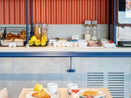 Um buffet de café da manhã com pães, frutas e bebidas.
