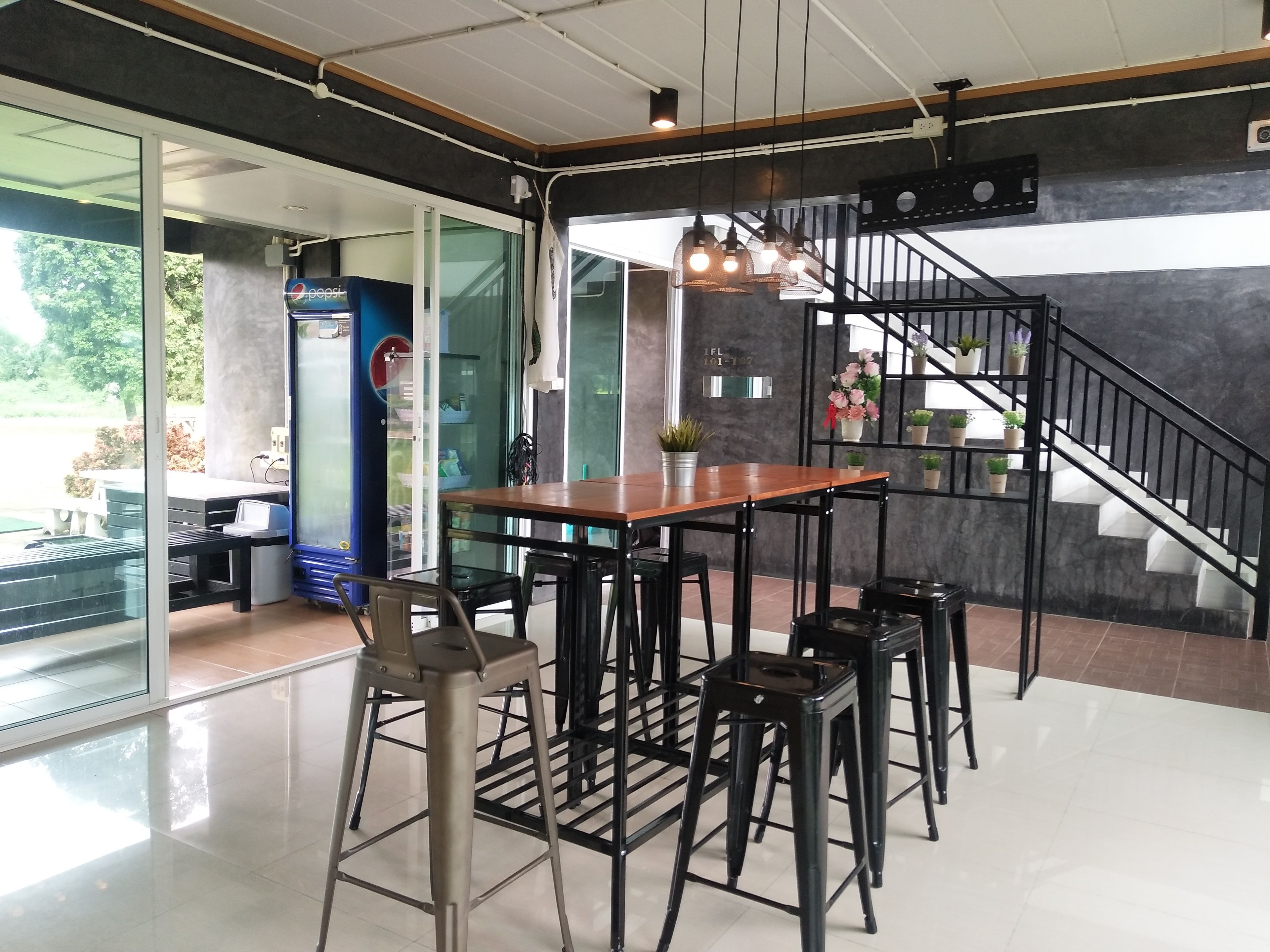 Decoração moderna com mesa de madeira e banquetas pretas, escada e porta de vidro que dá para o exterior.